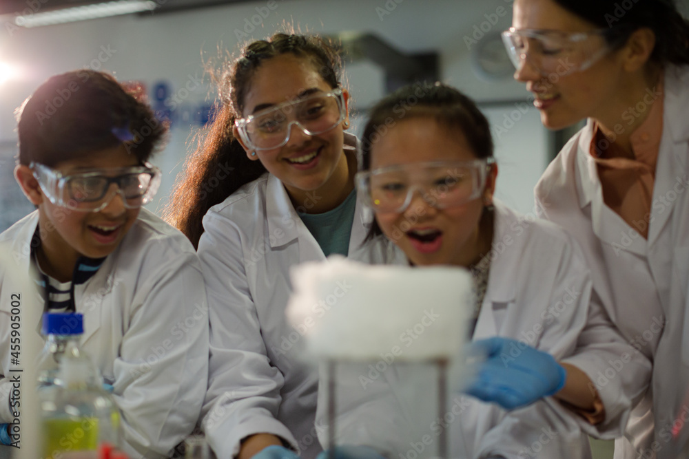 Female teacher and students watching scientific experiment chemical ...