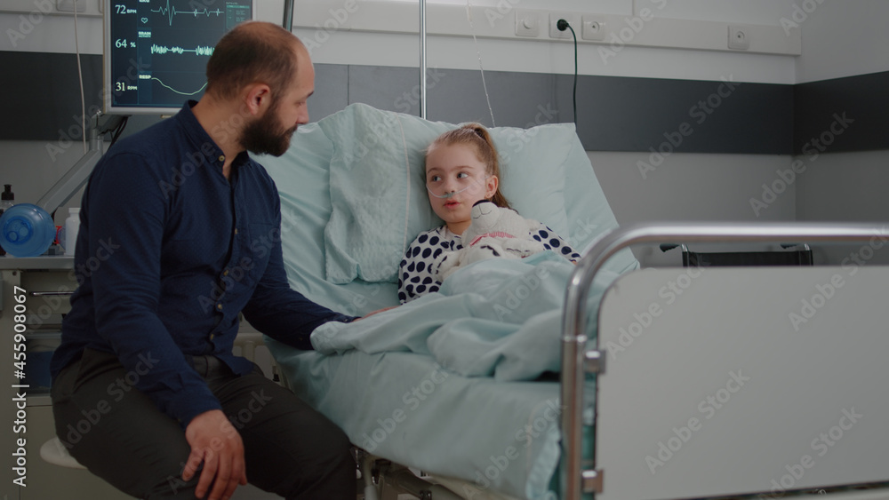 Sick girl child lying in bed discussing with worried father during ...