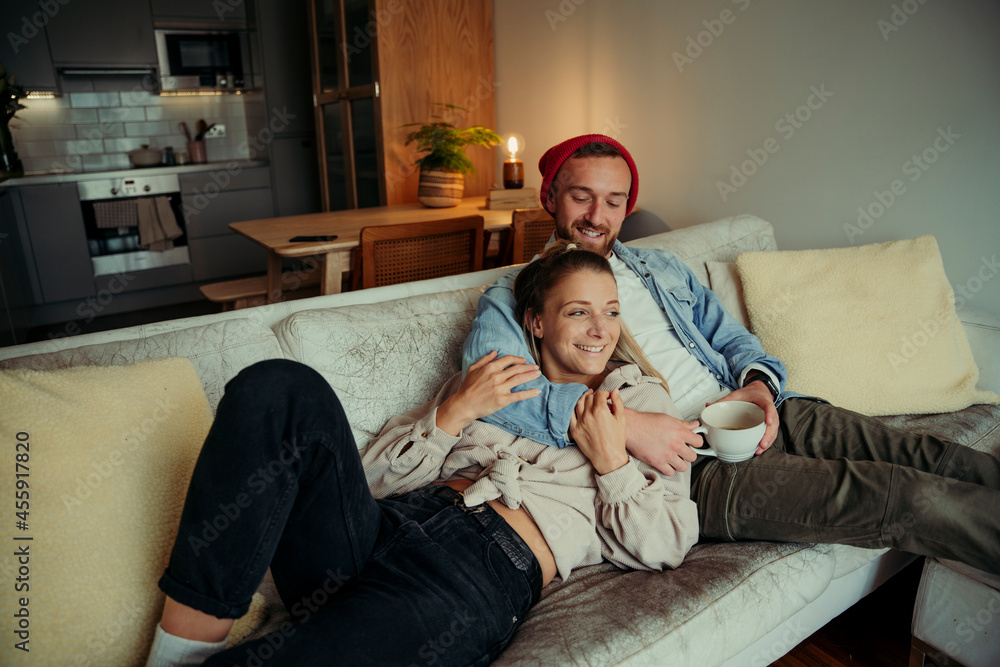 Caucasian couple cuddling on couch hugging each other and smiling Stock ...