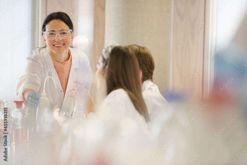 Female teacher and students conducting scientific experiment, watching ...