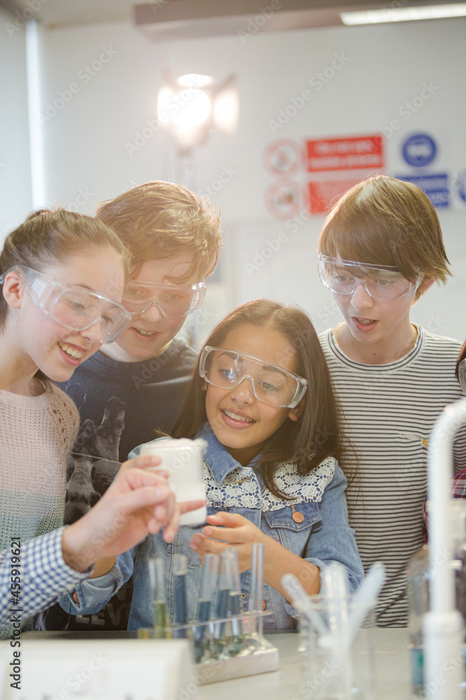Curious, smiling students watching chemical reaction, conducting ...
