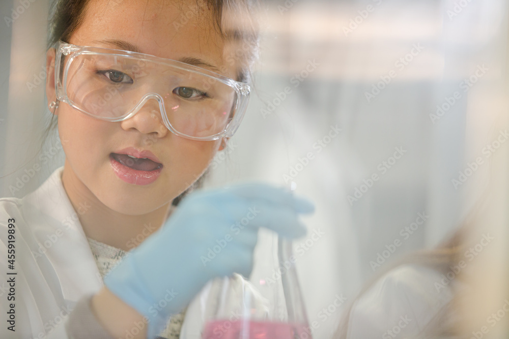 Girl student examining pink liquid, conducting scientific experiment in ...
