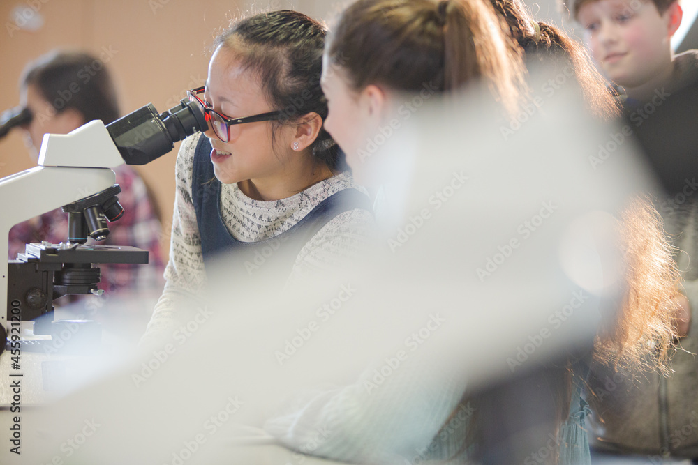 Girl students using microscope, conducting scientific experiment in ...