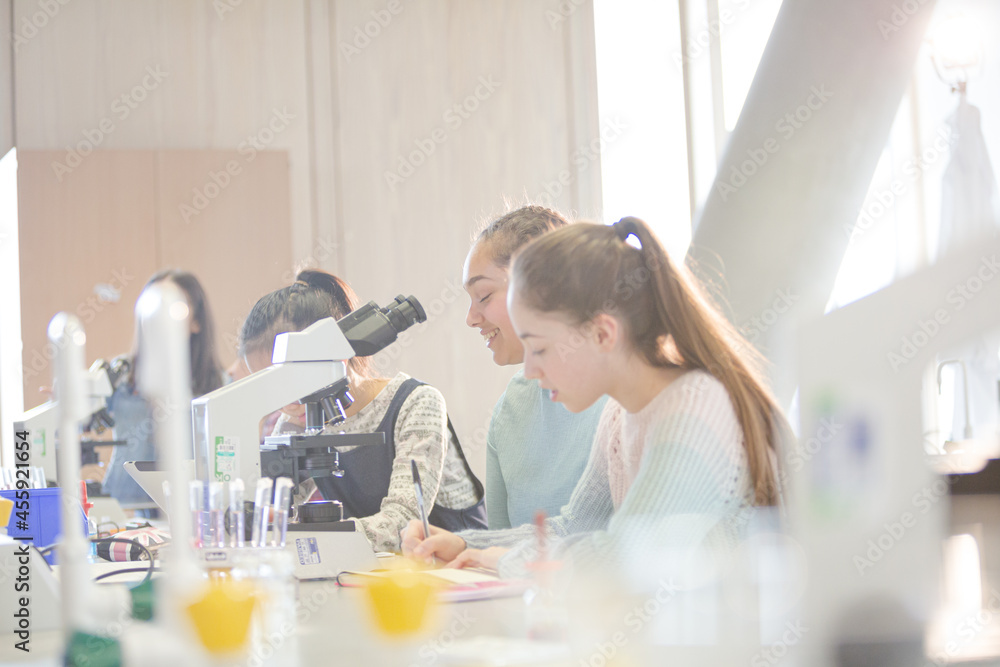 Girl students using microscope, conducting scientific experiment in ...
