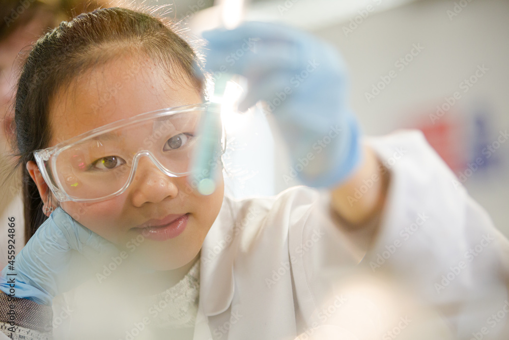 Girl students conducting scientific experiment, examining liquid in ...