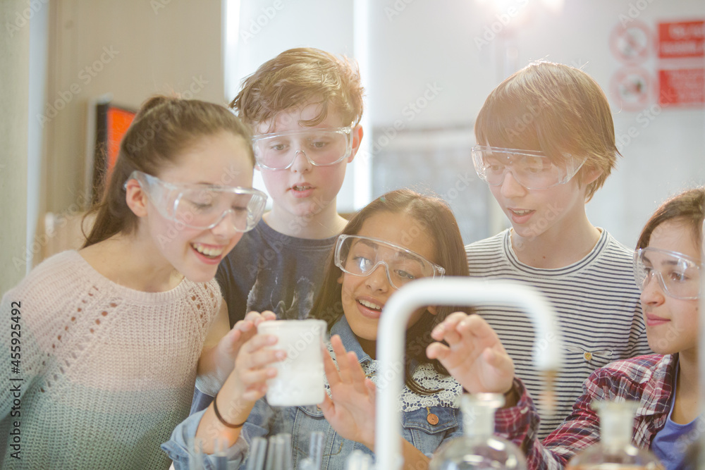 Curious, smiling students watching chemical reaction, conducting ...