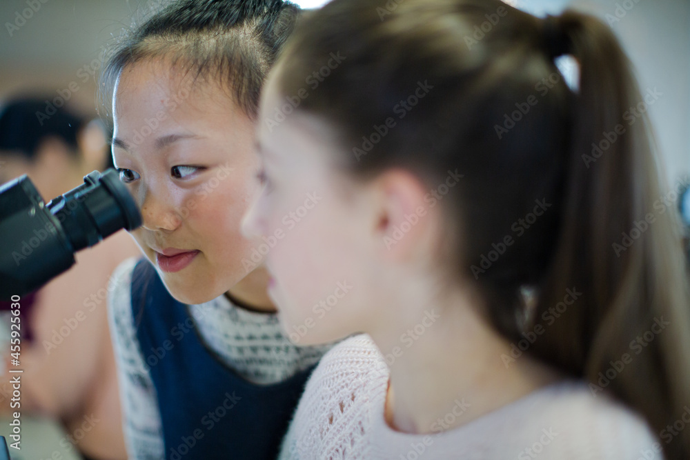 Girl students using microscope, conducting scientific experiment in ...