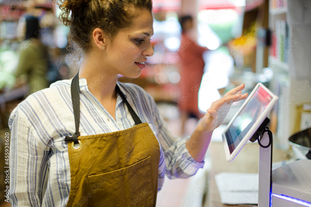 Female cashier using touch screen cash register in grocery store Stock ...