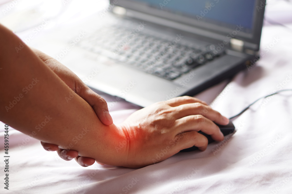Woman holds her wrist pain from using laptop computer's mouse. Concept ...