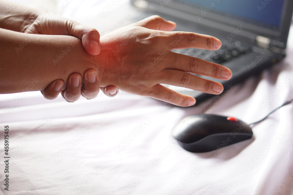 Woman holds her wrist pain from using laptop computer's mouse. Concept ...