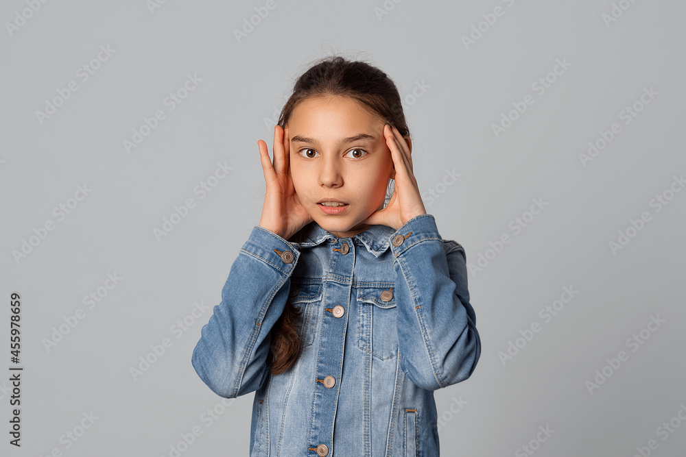 Confused young girl clutching her head in panic, isolated on grey ...