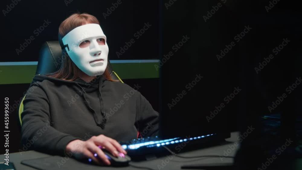 The hacker girl at the computer removes the mask from her face and ...