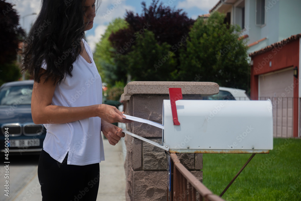Stockfoto young woman checking old-fashioned mailbox at the front yard ...