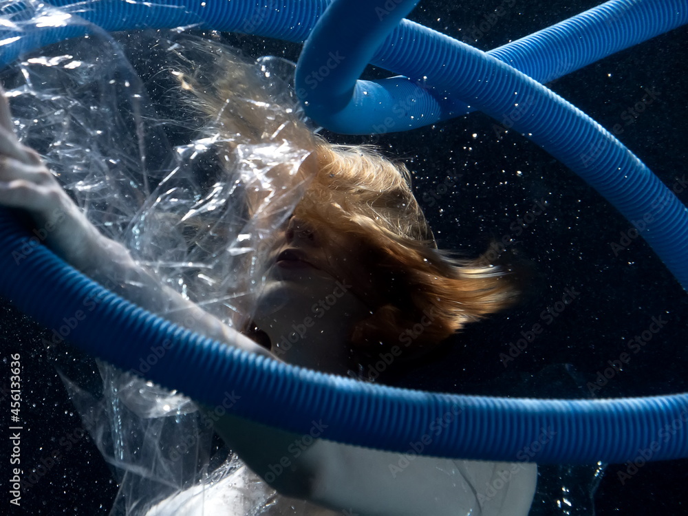 Foto de Woman swimming underwater among plastic trash. Girl drowning in ...