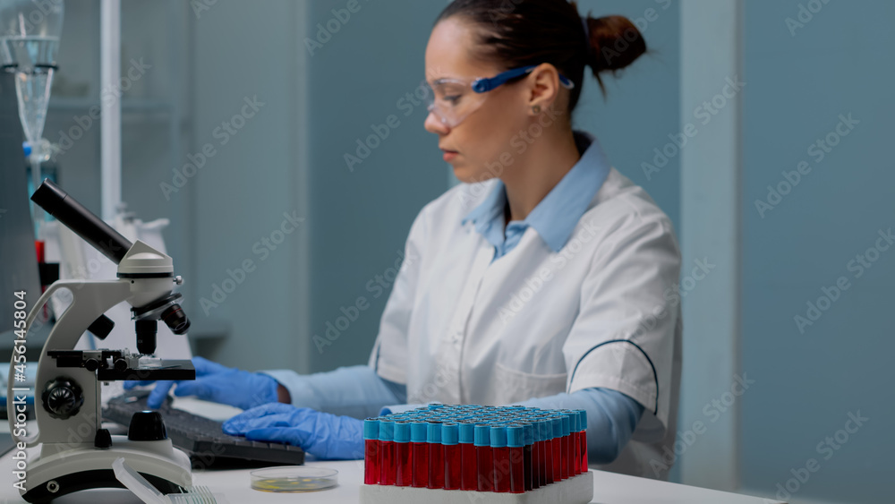 Microbiology specialist using computer in laboratory while having ...