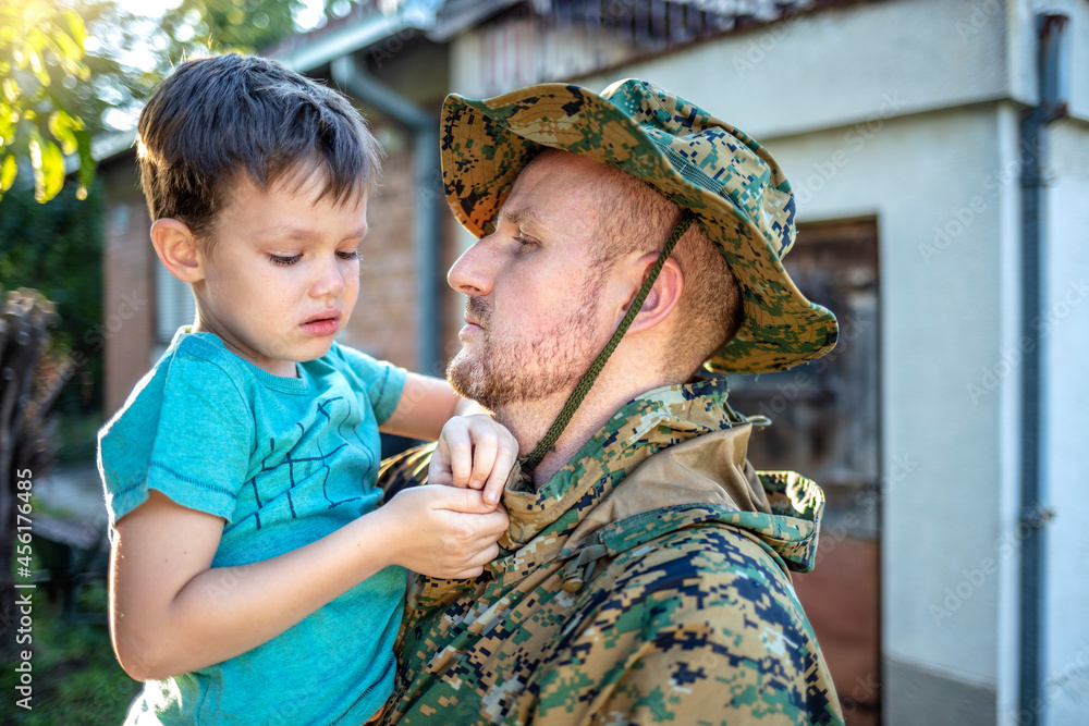 Crying little boy and soldier in a military uniform say goodbye before ...