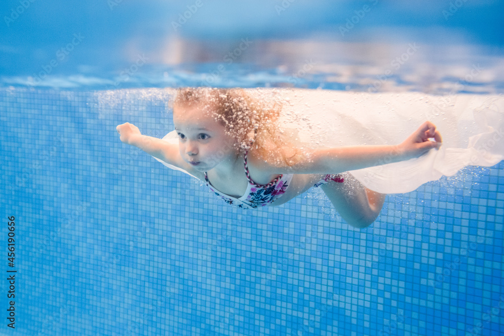 Little child girl swimming underwater in the paddling pool. Diving ...