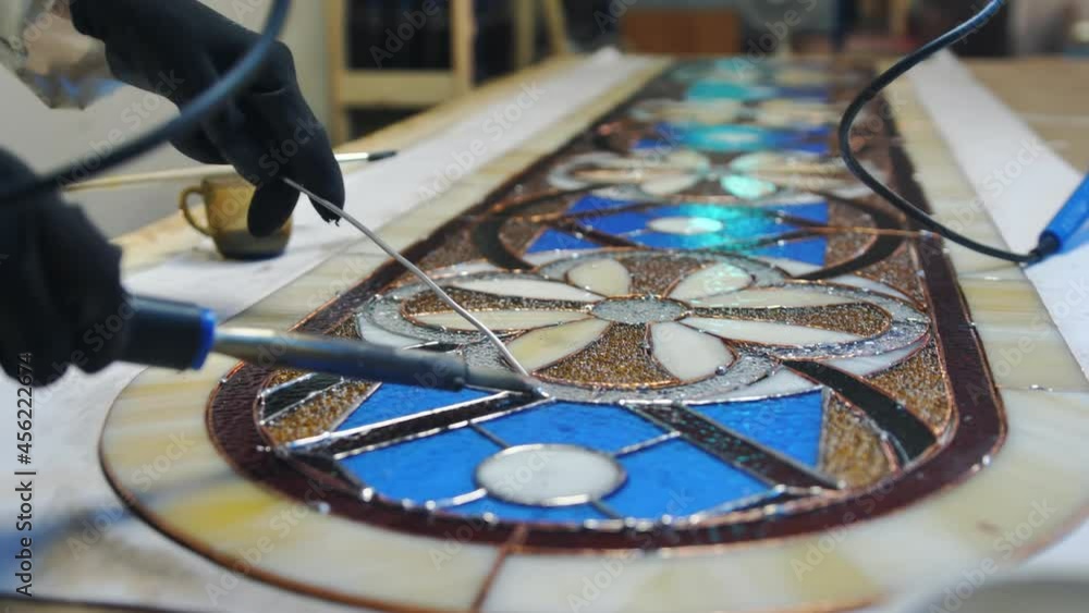 Soldering of stained glass seams. Gloved hands with a soldering iron ...