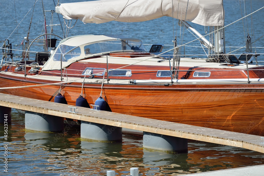 Elegant modern sailing boat with wooden teak deck moored to a pier in a ...