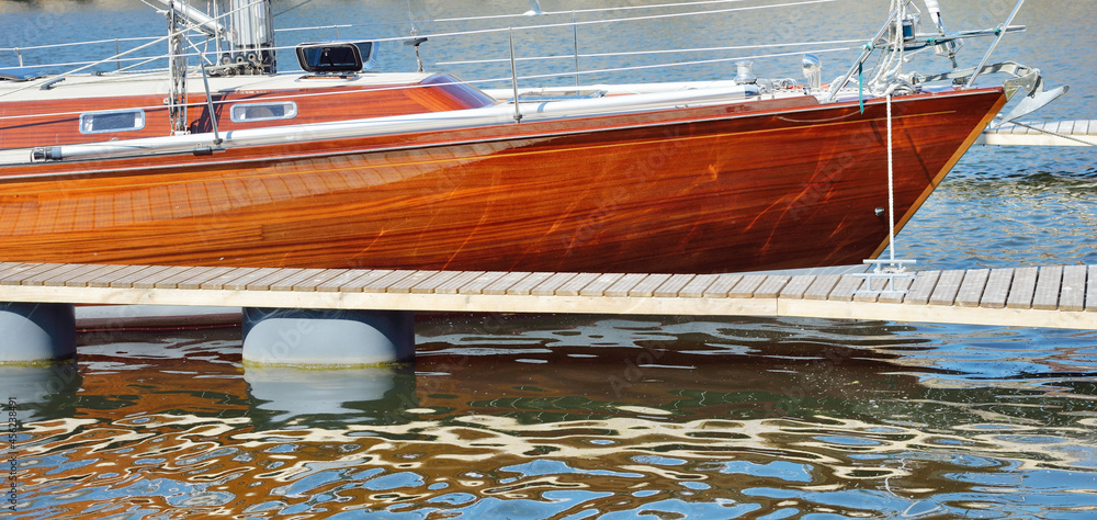 Elegant modern sailing boat with wooden teak deck moored to a pier in a ...