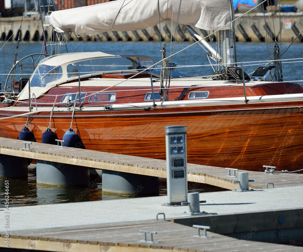 Elegant modern sailing boat with wooden teak deck moored to a pier in a ...