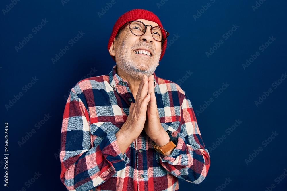 Handsome mature man wearing hipster look with wool cap begging and ...