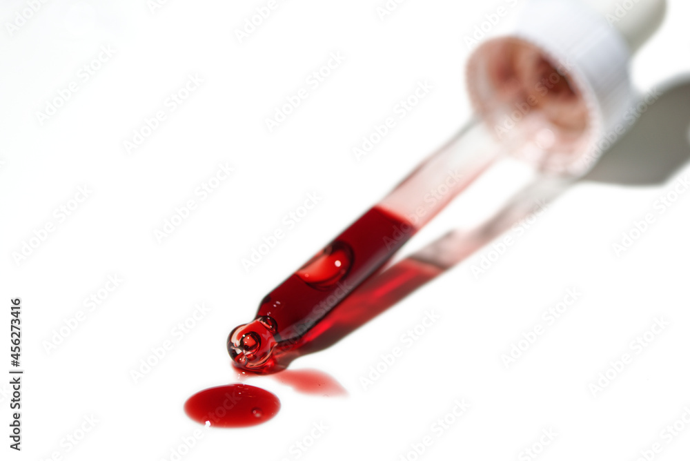 Liquid red oil serum drop in pipette isolated on white background ...