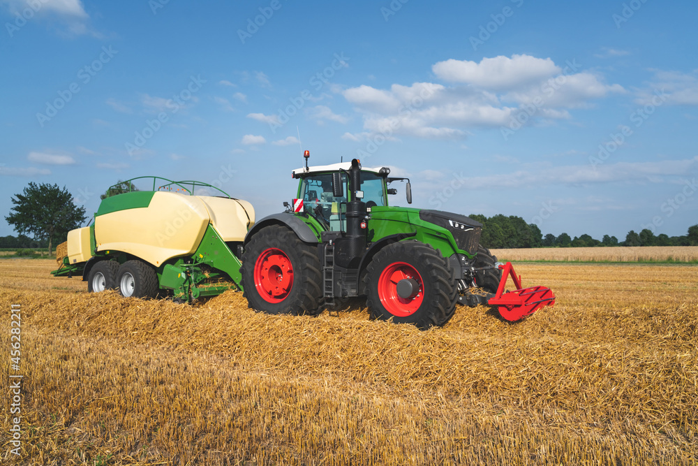Strohernte - Traktor mit moderner Hochdruckpresse beim Pressen von ... Strohernte - Traktor mit moderner Hochdruckpresse beim Pressen von ...