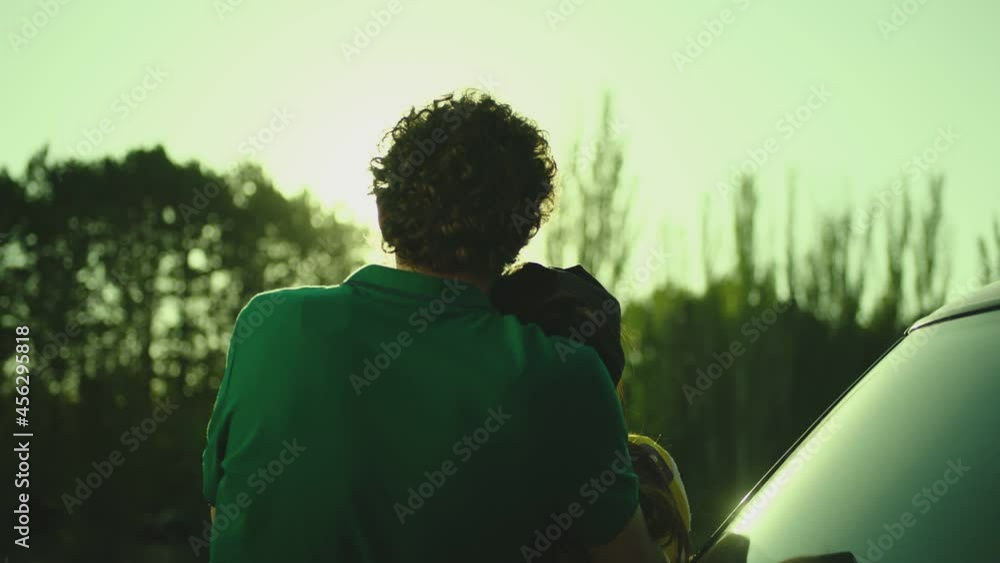 Back rear view of young couple sitting in auto car hood looking at ...