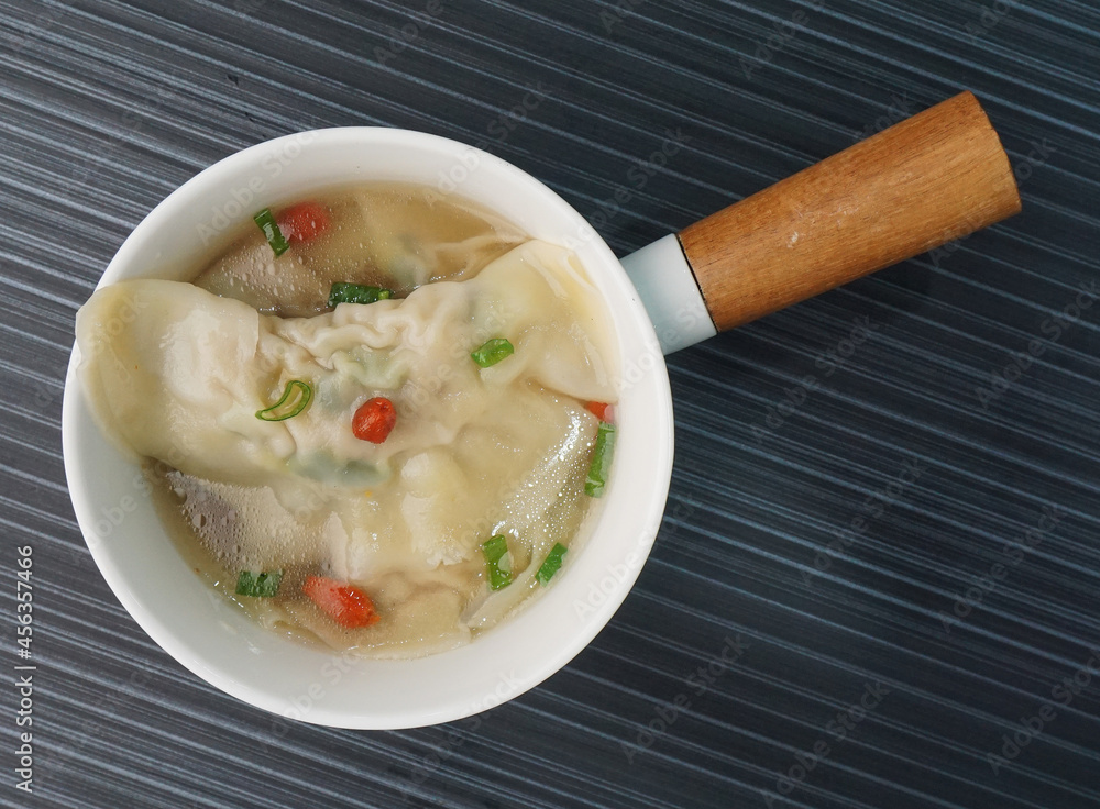 handmade deep fried and boiled pork meat dumpling wanton soup on dark ...