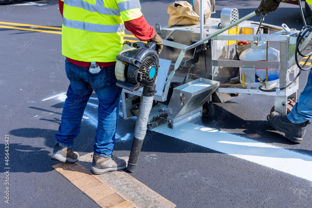 Road worker painting white line on the street surface tor thermoplastic ...