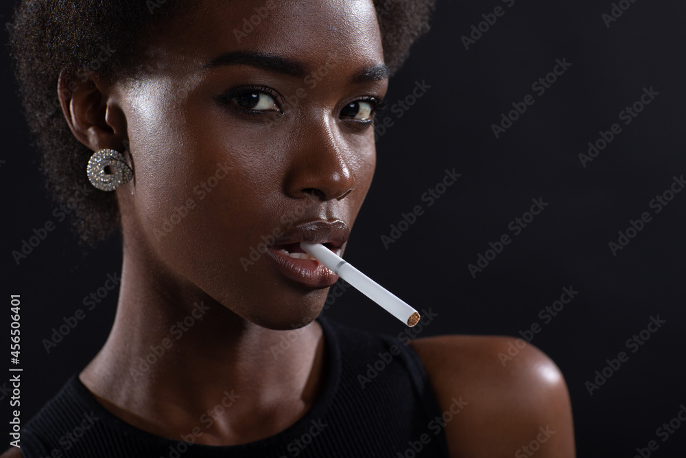 Sexy african american woman smoking cigarette on black dark background ...