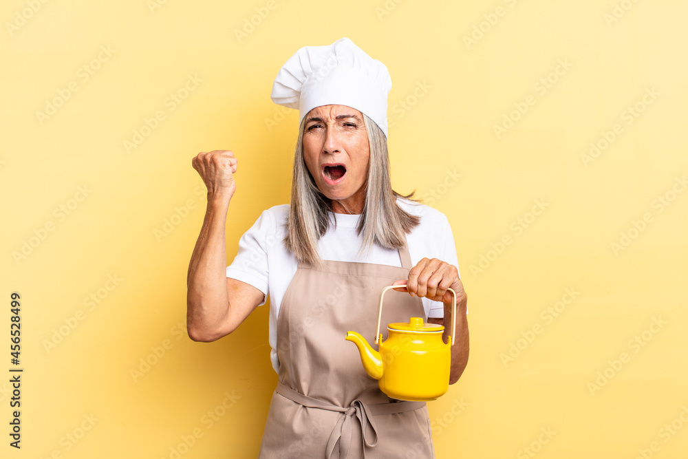 Foto de middle age chef woman shouting aggressively with an angry ...