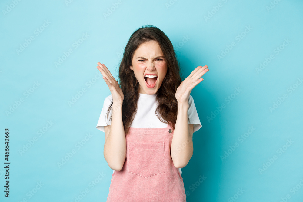 Angry and annoyed young woman screaming, frowning and looking outraged ...