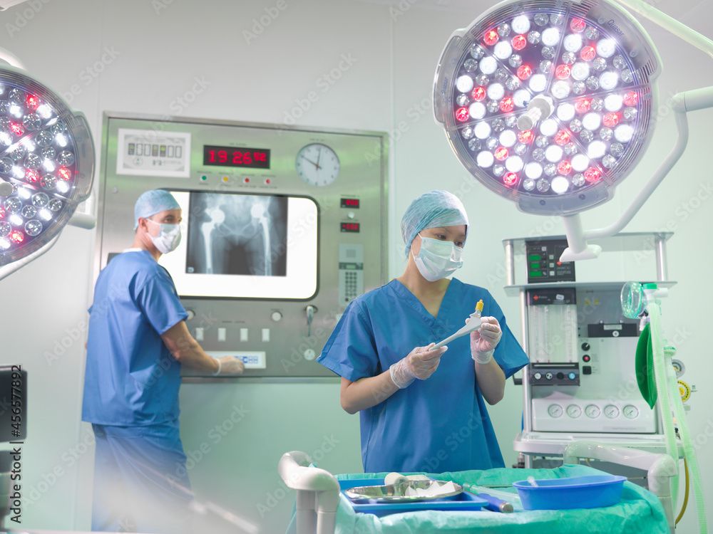 Orthopaedic surgeon and nurse with replacement hip stem in operating ...