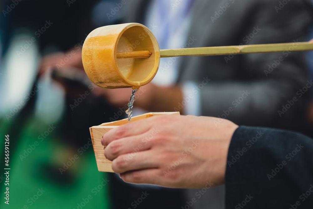 Details with the hands of a man pouring traditional Japanese sake in a ...