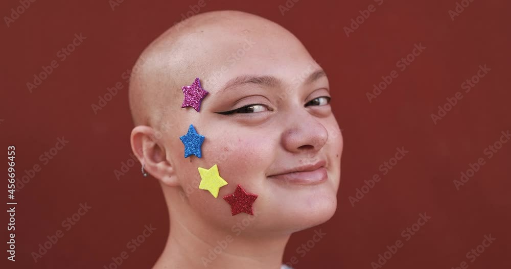 Bald girl with colorful stars on her face posing in front of camera ...
