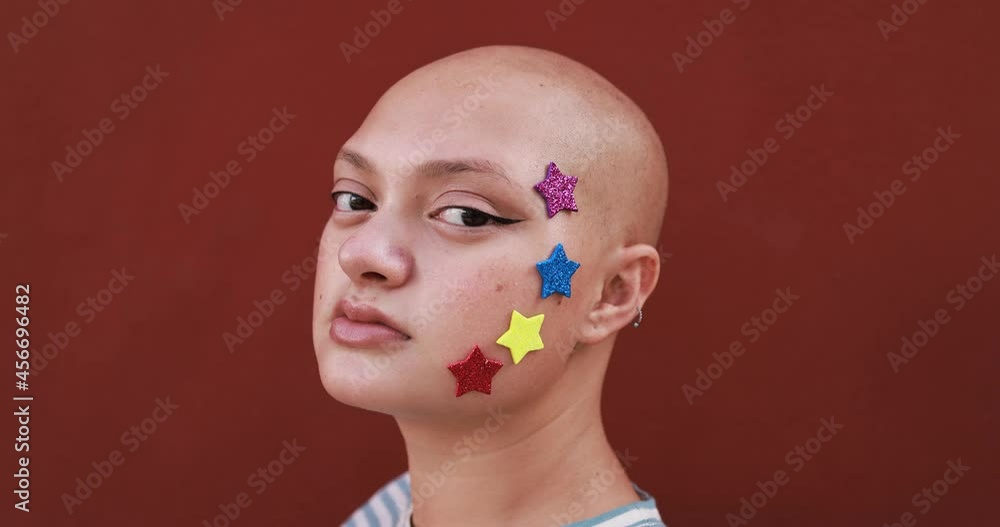 Bald girl with colorful stars on her face posing in front of camera ...