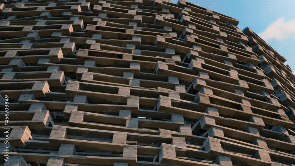 A tower of wooden pallets stacked high on top of each other ready to ...