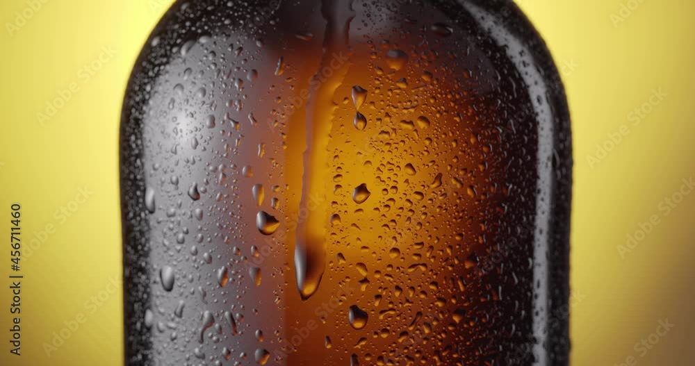 Beer drop slowly trickles down the misted beer bottle, following the ...