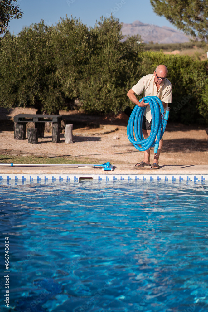 Old man with hose on poolside on backyard Stock Photo | Adobe Stock