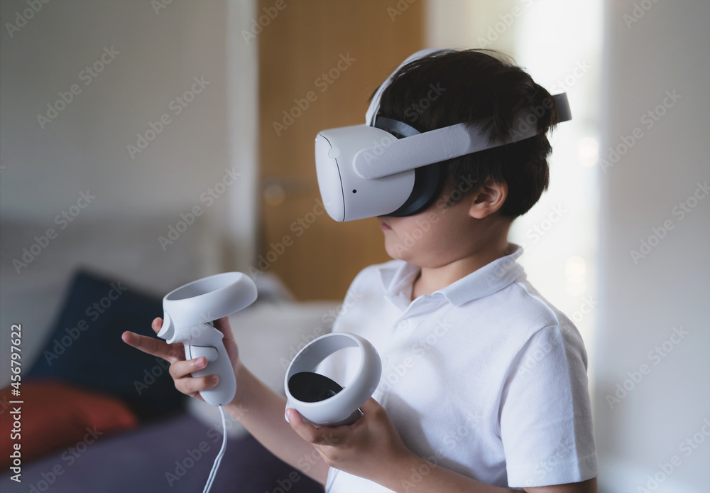 Amazed young kid wearing virtual reality goggles. Emotional Boy playing ...