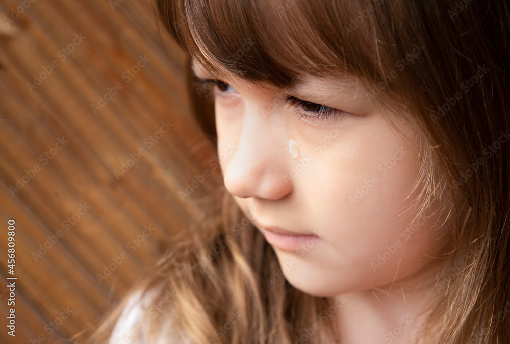 The girl is crying. A child with a sad face and a tear on his cheek ...