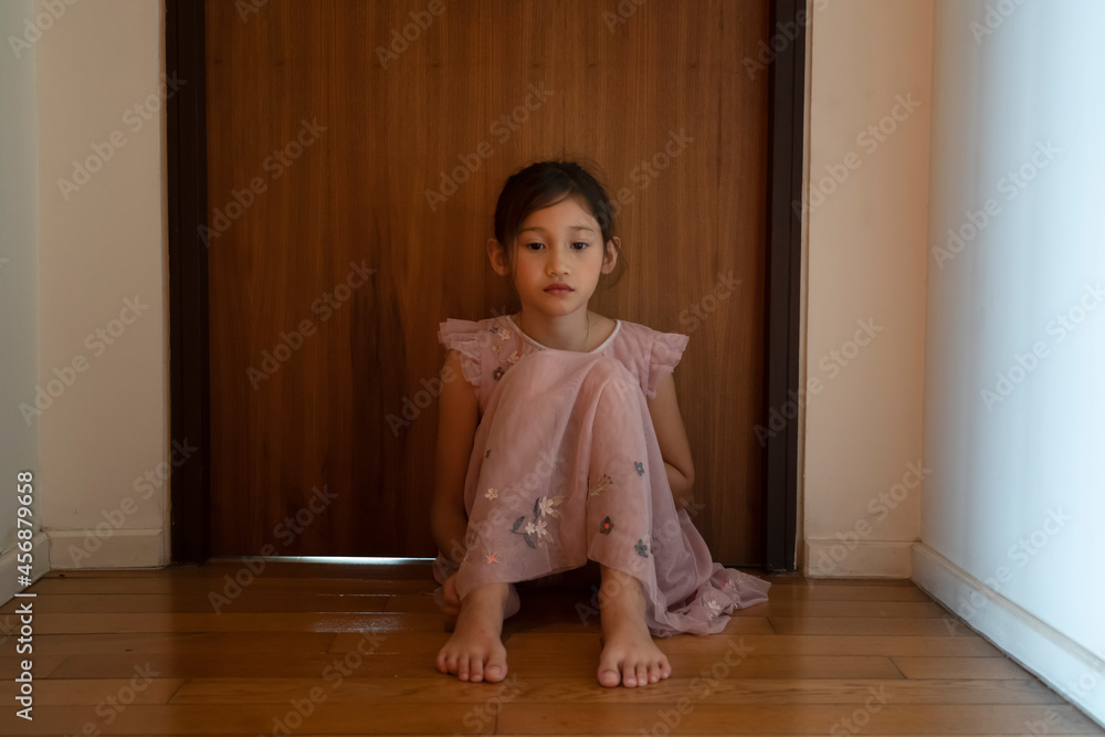 Sadness offended little girl scared. A Child sitting in a dark corridor ...
