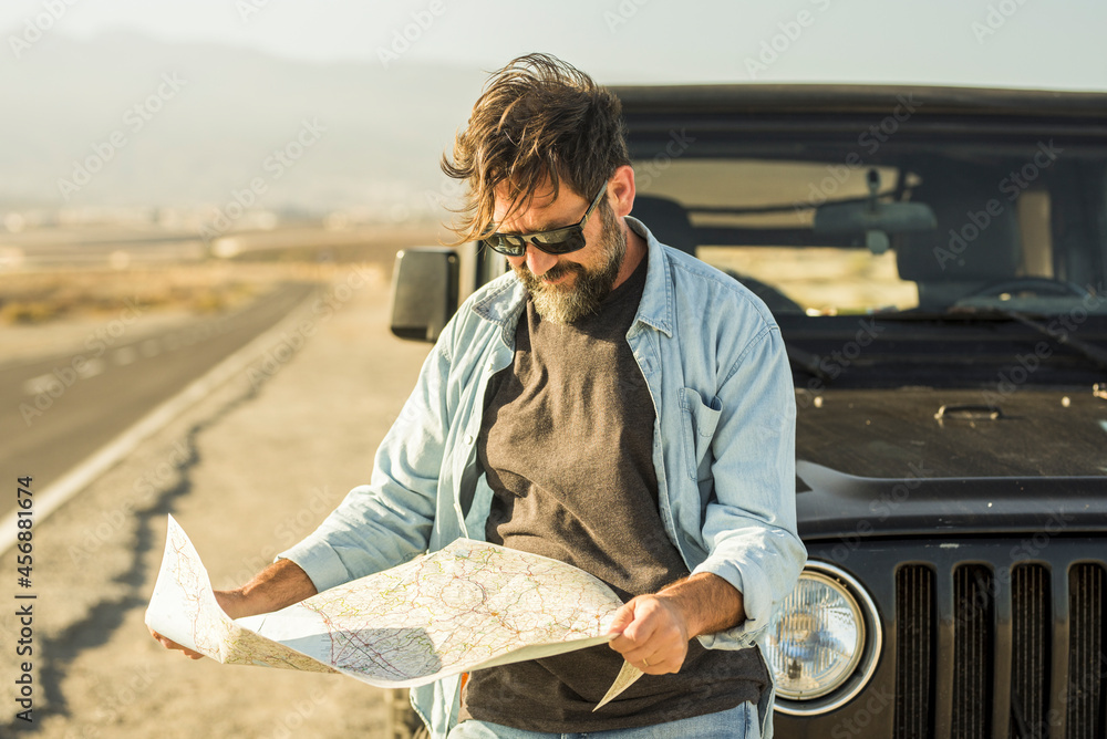 Man looking at map leaning on vehicle at roadside. Mature man checking ...