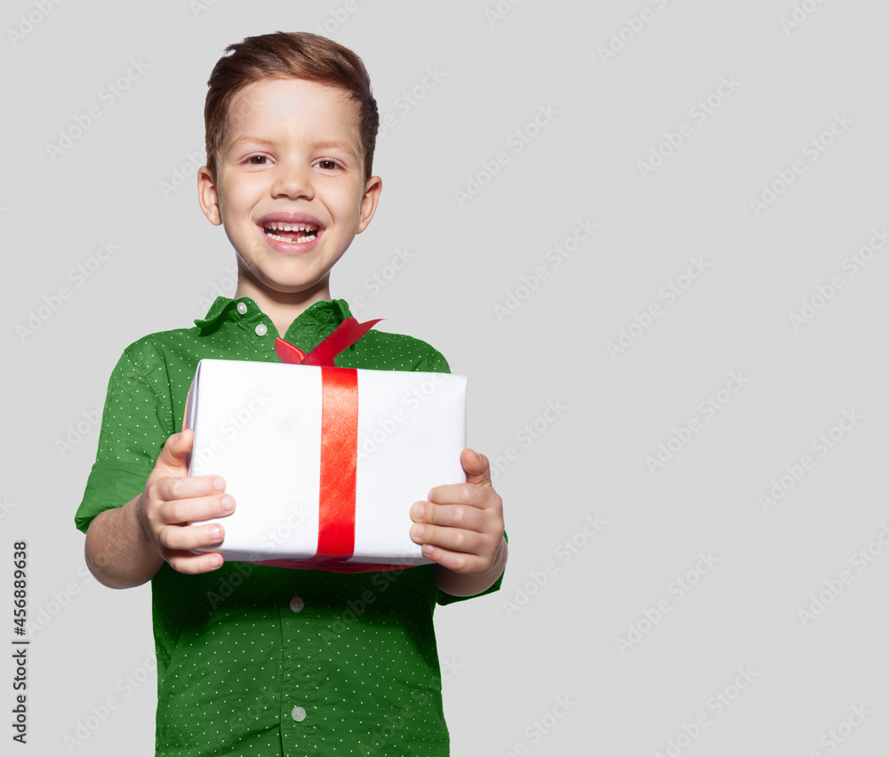 Joyful little boy with festive gift surprise celebrating holiday on ...