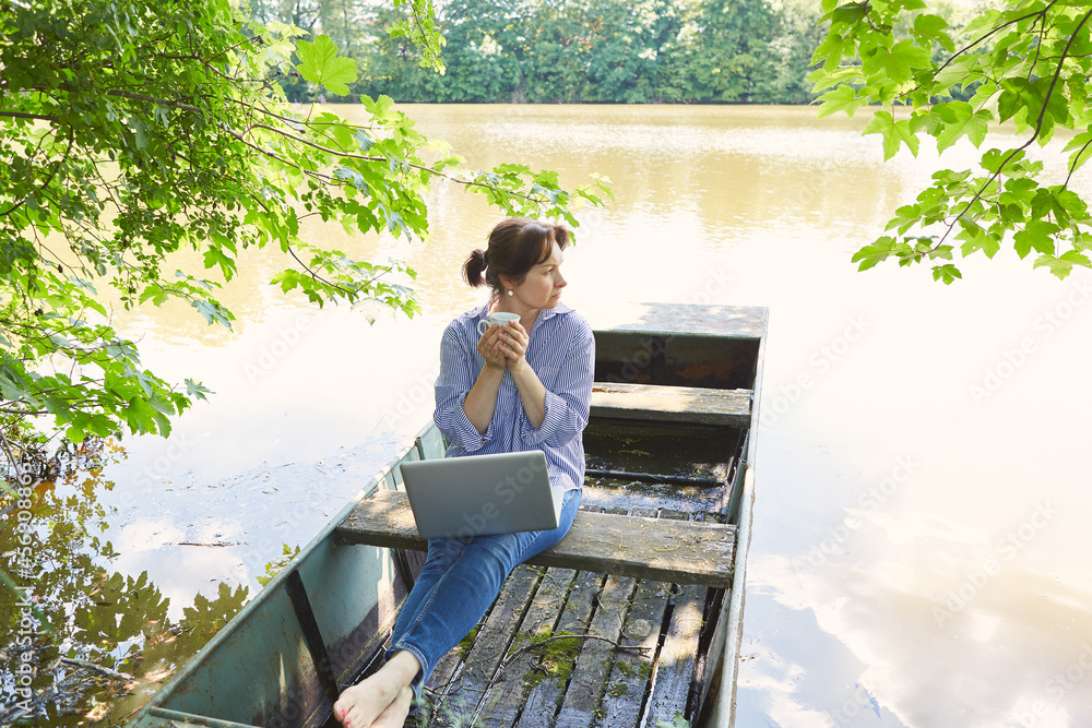 Frau mit Laptop beim Tagträumen in Boot am See Stock Photo | Adobe Stock