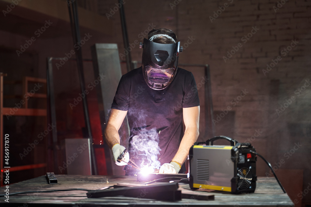 the process of welding two pieces of iron. welder in a black helmet at ...