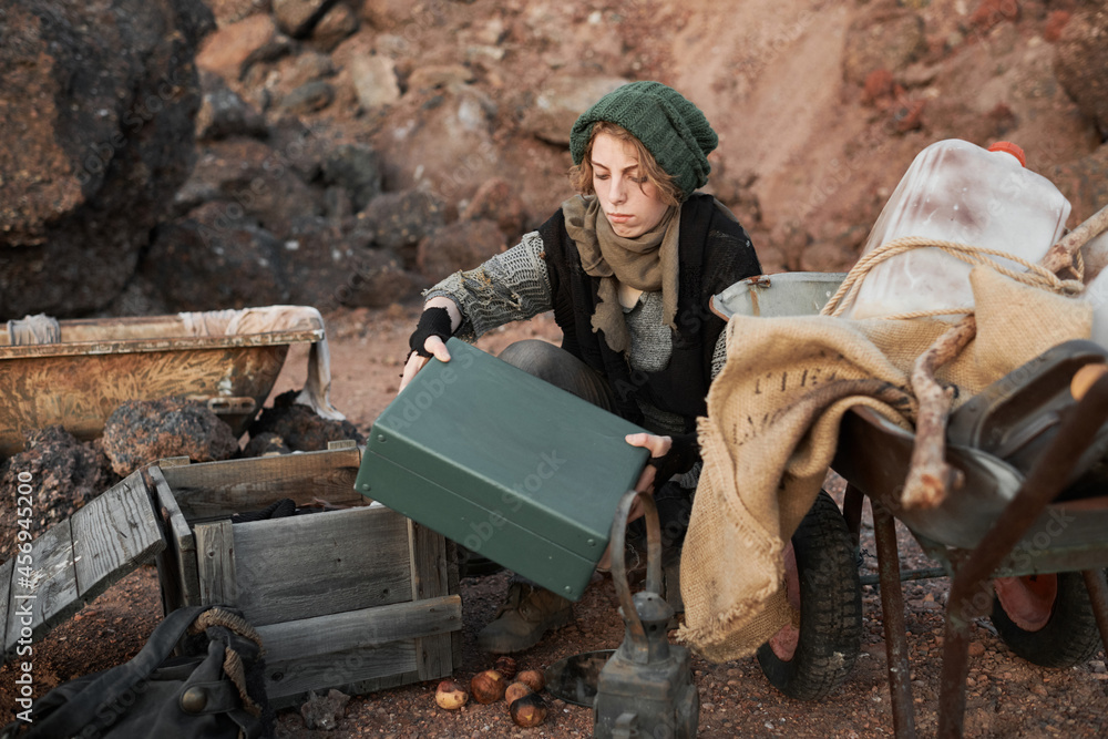 Young homeless woman in torn clothes taking the box out among her ...