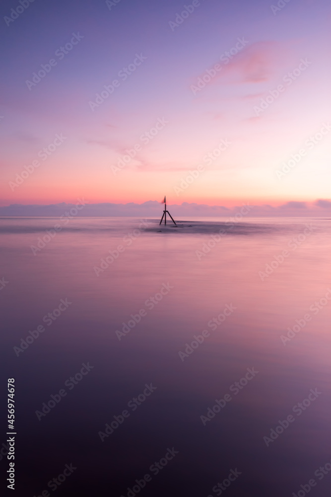 Metal tide gauge at the beach at high tide and after sunset. Seascape ...